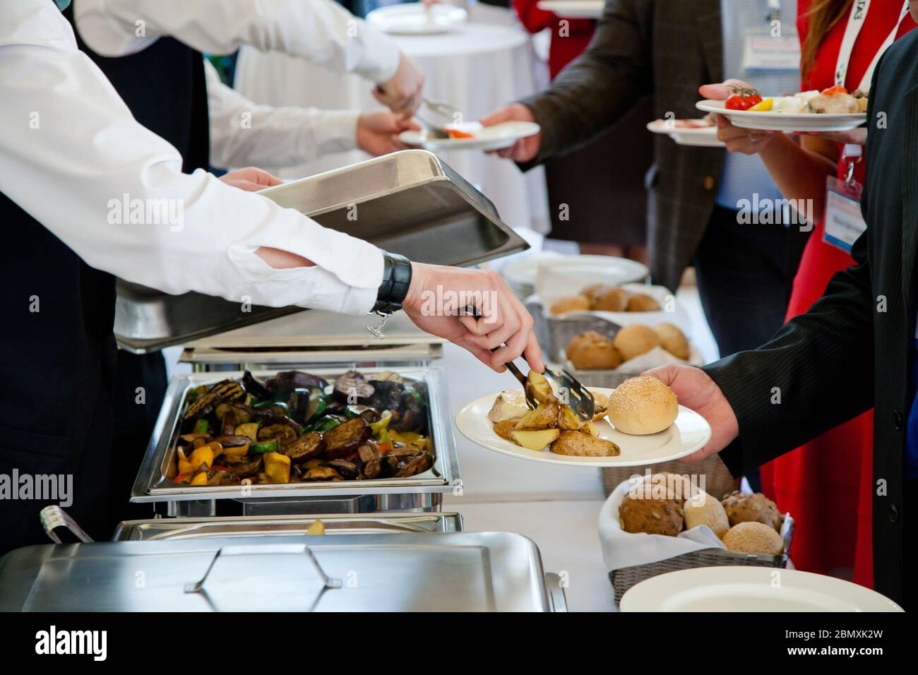 People at the reception taking food on plates Stock Photo - Alamy