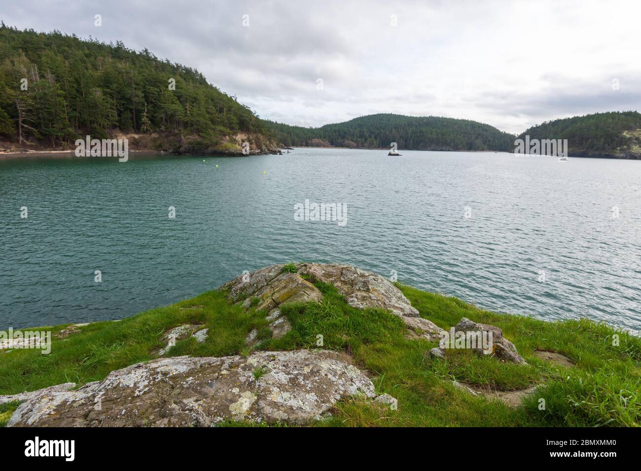 Landscape of water and forested hills from a grassy knoll Stock Photo ...