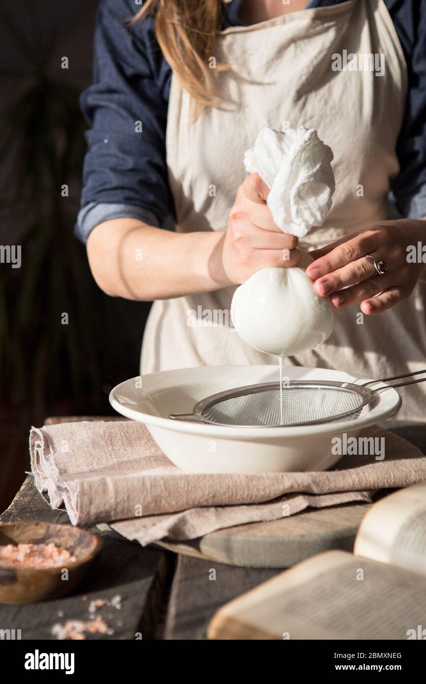 Preparation of cottage cheese - woman straining the milk through a ...