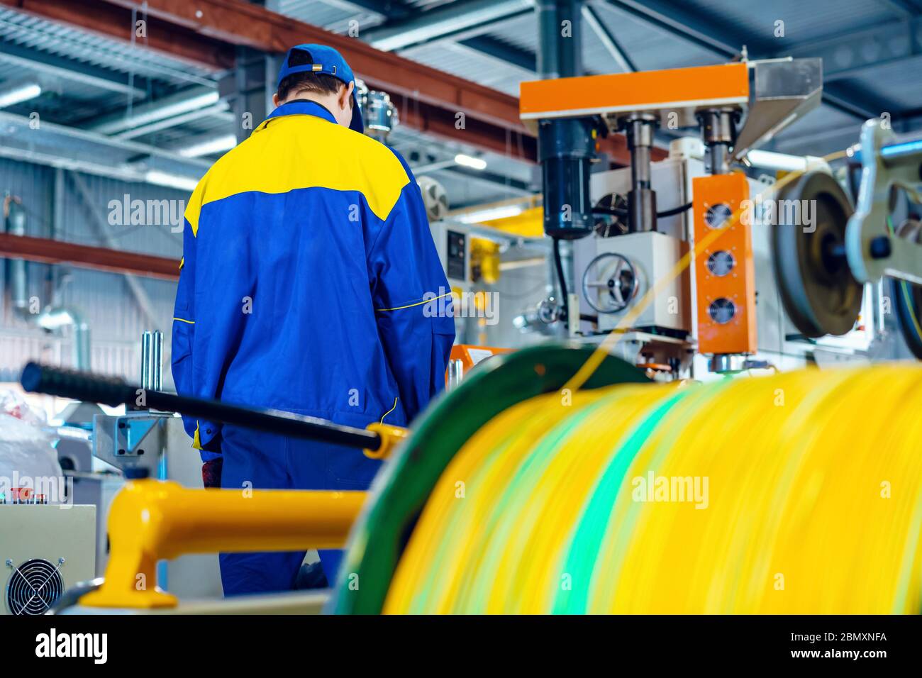 Man worker in manufacturing plant at cable factory machine control ...