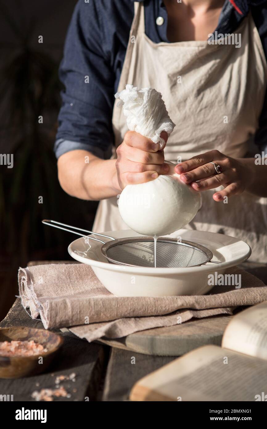 Preparation of cottage cheese - woman straining the milk through a ...