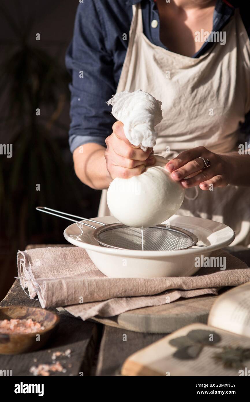 Preparation of cottage cheese - woman straining the milk through a ...