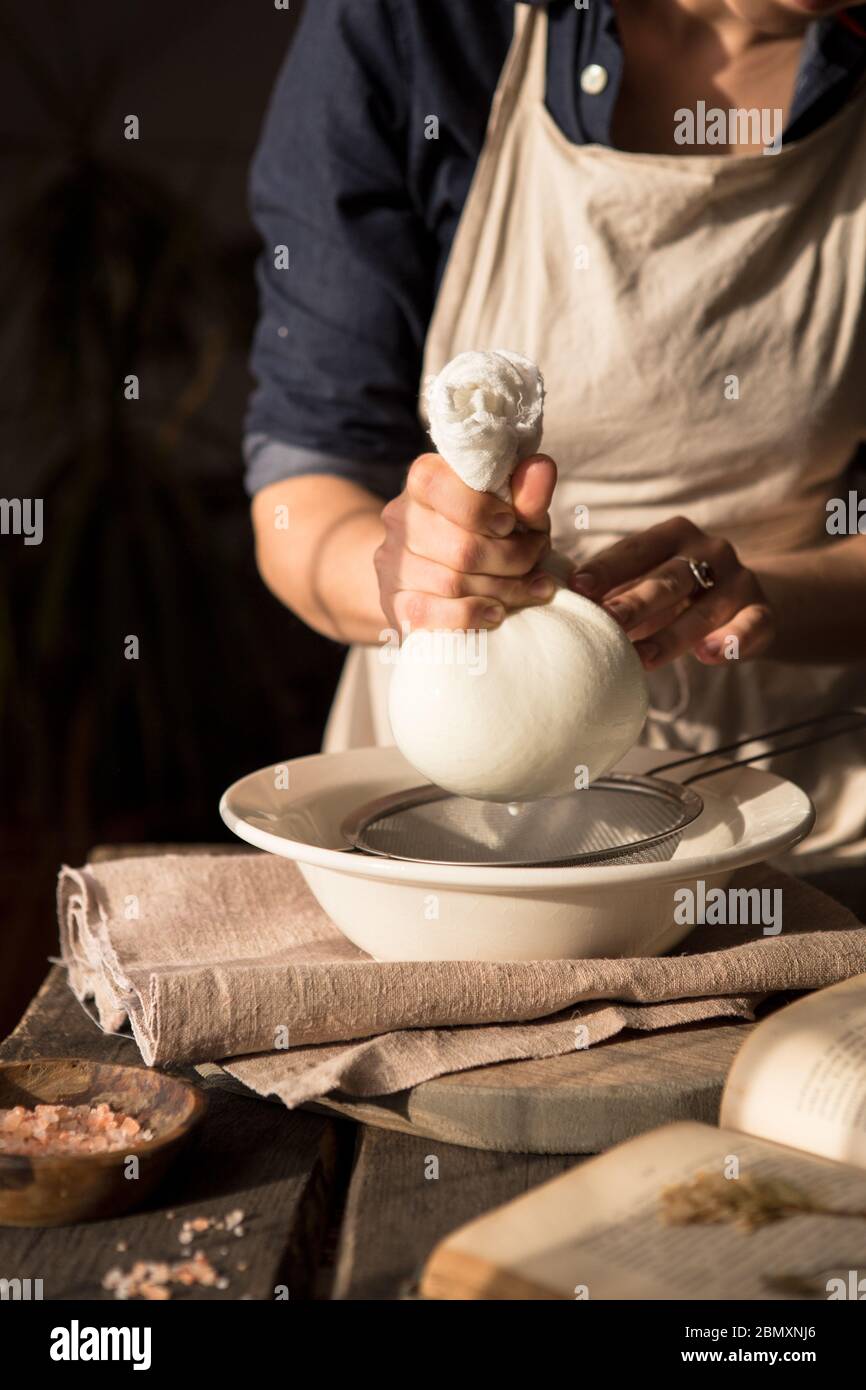 Preparation of cottage cheese - woman straining the milk through a ...