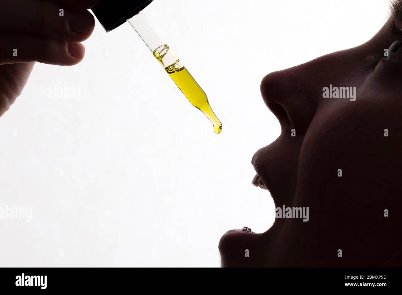 Silhouette of a woman taking drops of CDB oil Stock Photo - Alamy