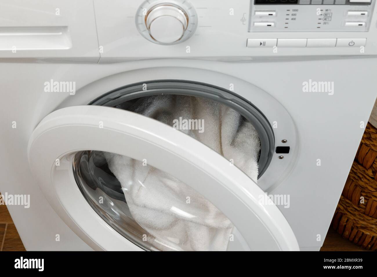 Washing machine with laundry on blue wall background Stock Photo - Alamy