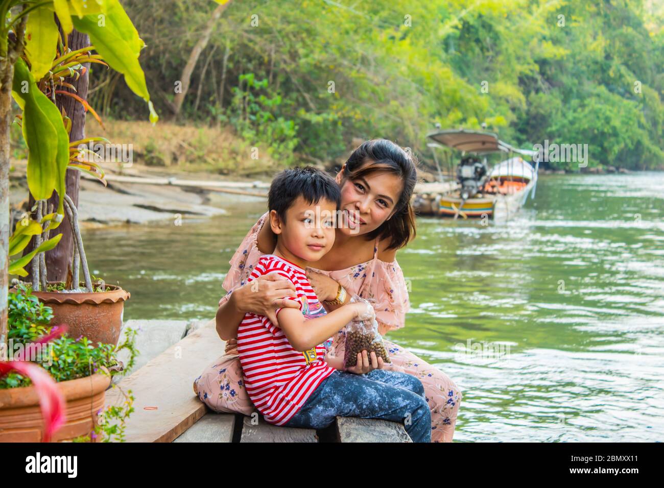 Mother and son sit to feed the fish Stock Photo - Alamy
