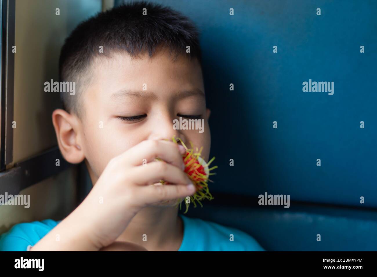 Images like a boy sitting eating Rambutan Stock Photo - Alamy
