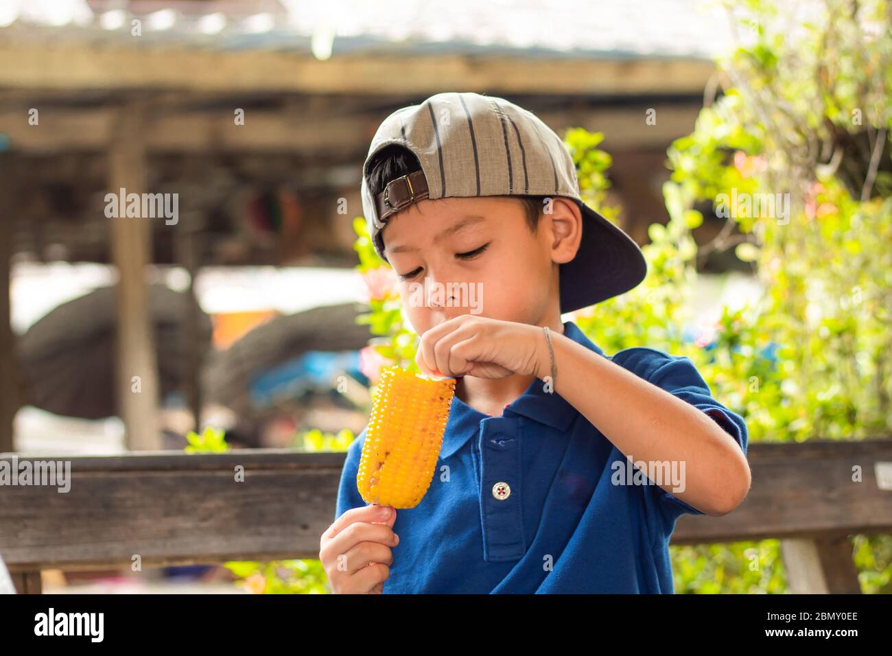 Asian boy are eating grilled corn Stock Photo - Alamy