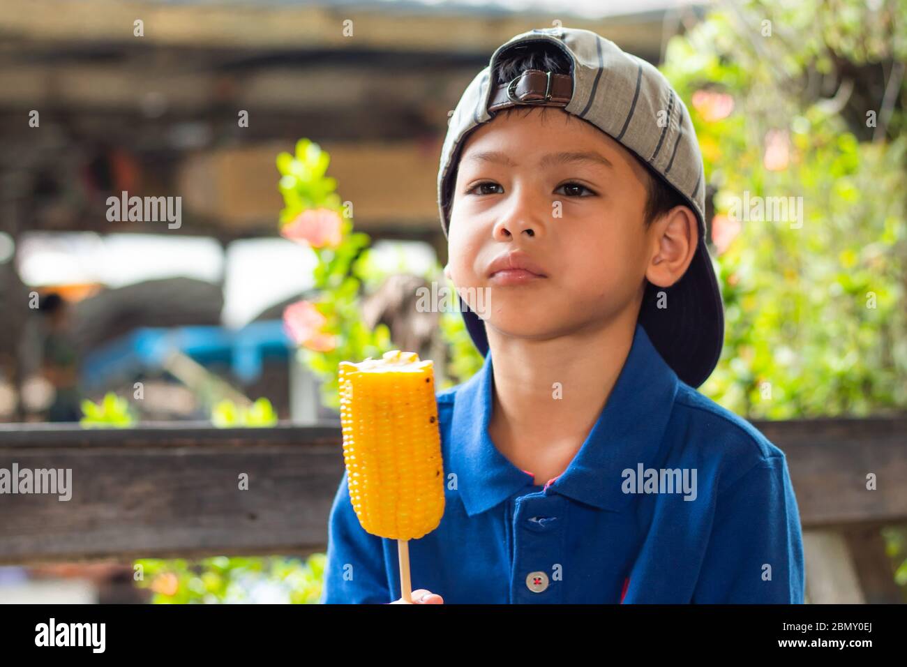Asian boy are eating grilled corn Stock Photo - Alamy
