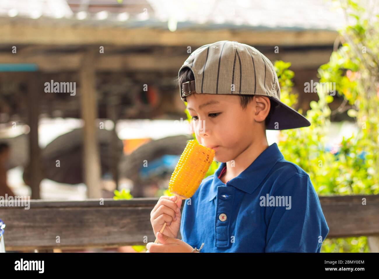Asian boy are eating grilled corn Stock Photo - Alamy