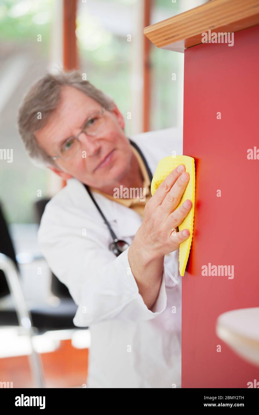 Mature doctor cleaning the furniture in his office - selective focus on ...