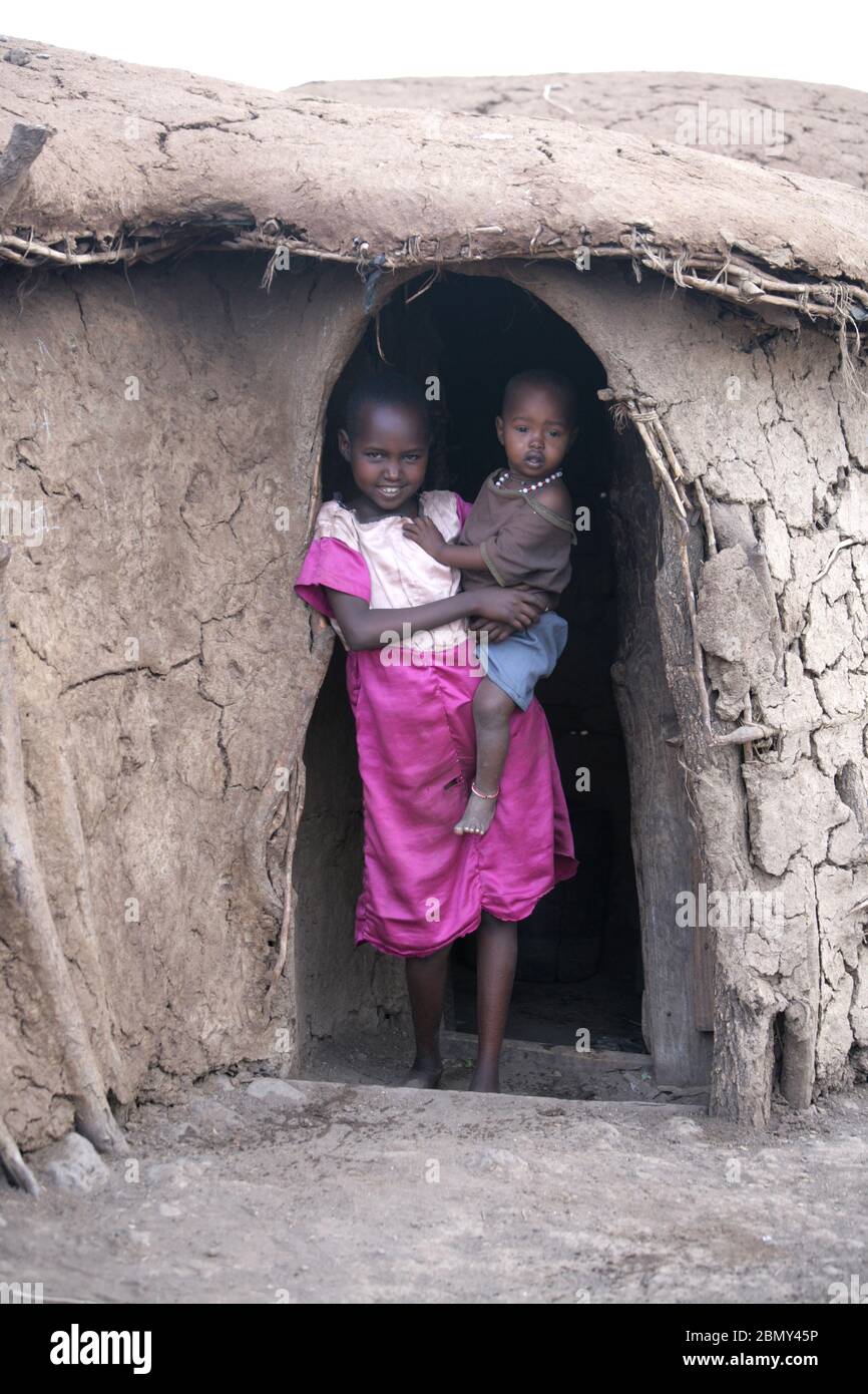 Masai children. Masai girl with her toddler sister at the doorway to ...