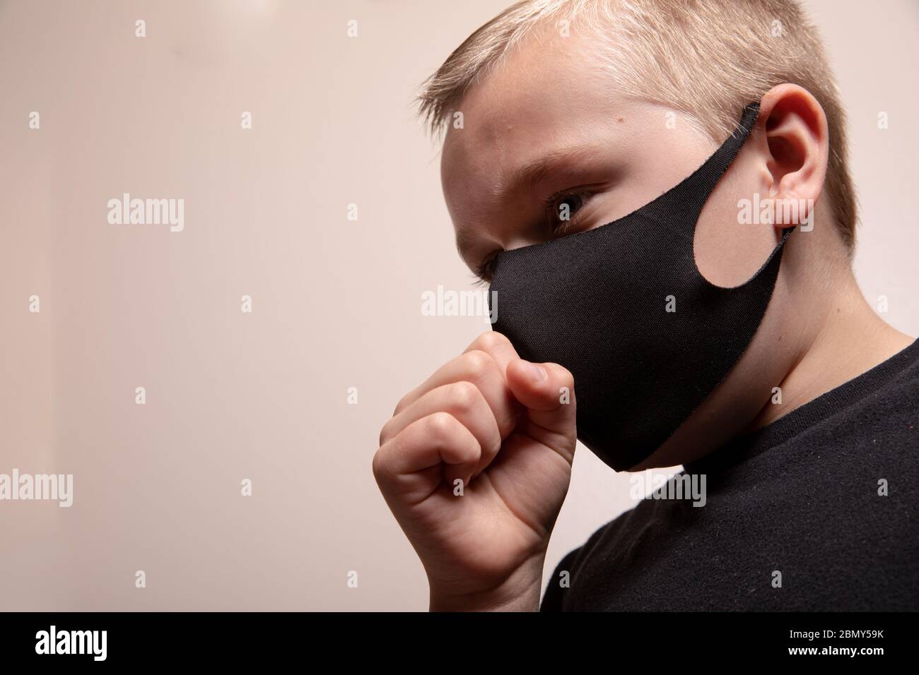 sick young boy coughing into his hand and his mask Stock Photo - Alamy