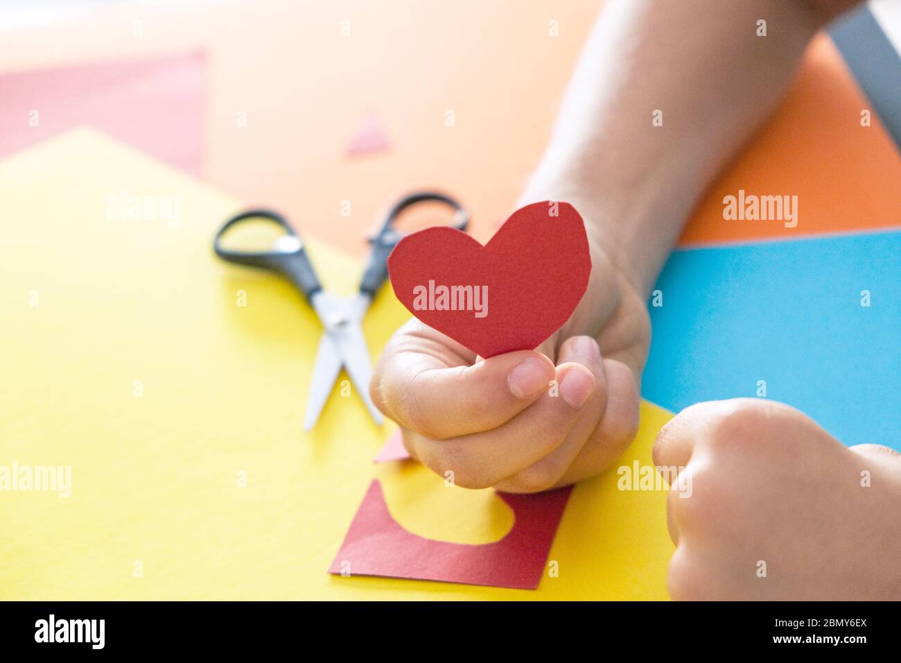 Paper crafts for kids. Child hands cuts colored paper with scissors and ...