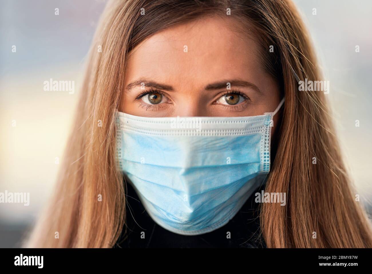 Young woman wearing blue disposable mouth face nose virus mask, closeup ...