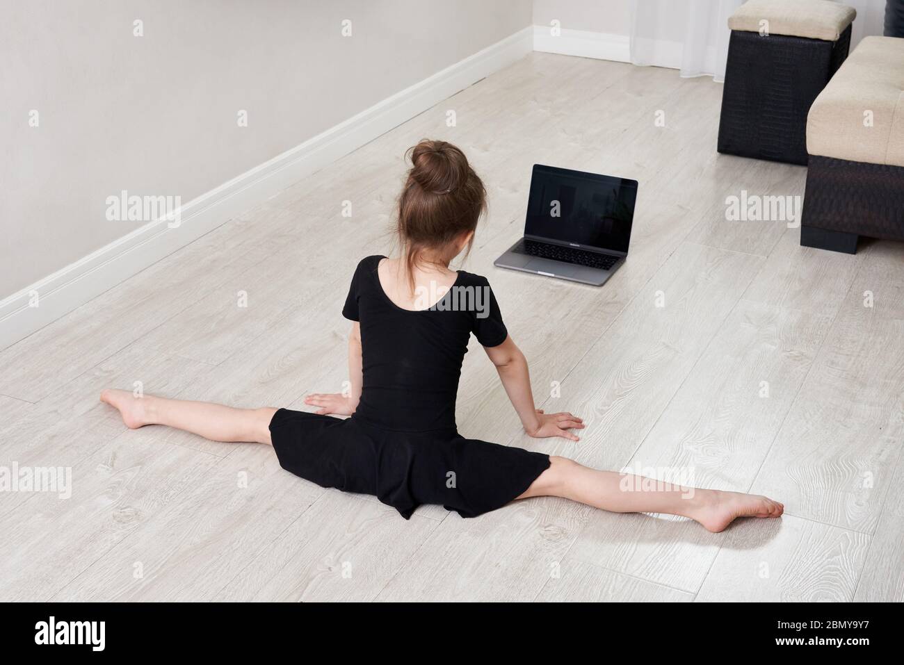 girl training at home, doing gymnastics and split on a floor, watching ...