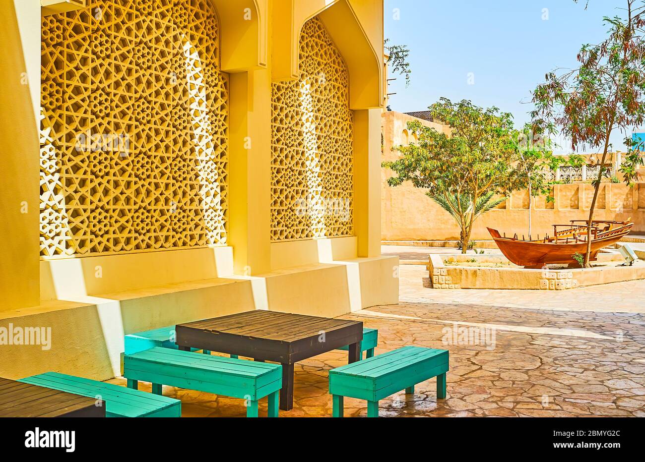 The shady street with wooden benches and tables, Arabic screen panels ...
