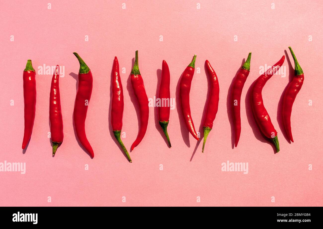 Red chilli peppers horizontal row on pink background. Top view. Hot ...