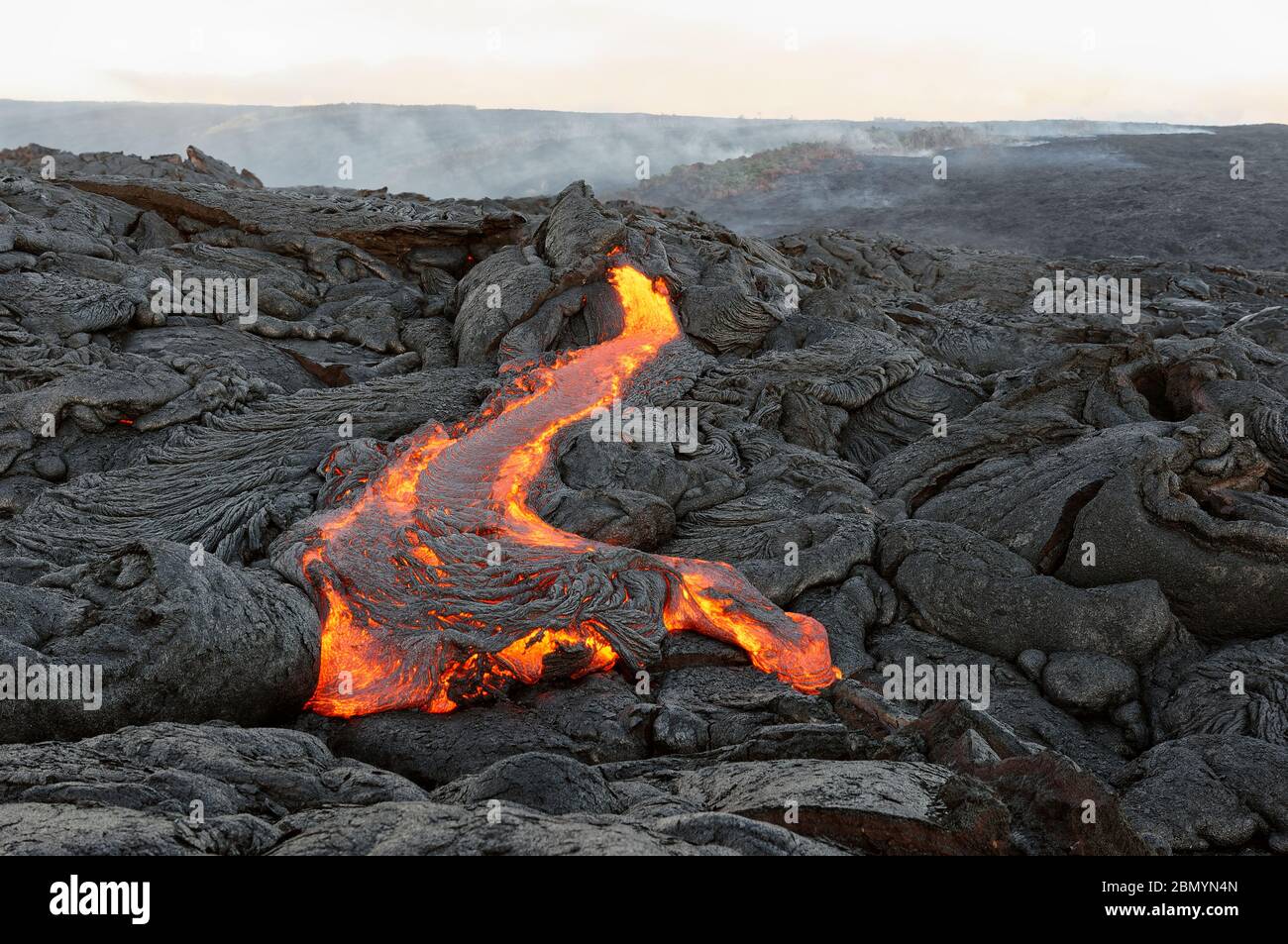 A lava flow emerges from an earth column and flows in a black volcanic ...