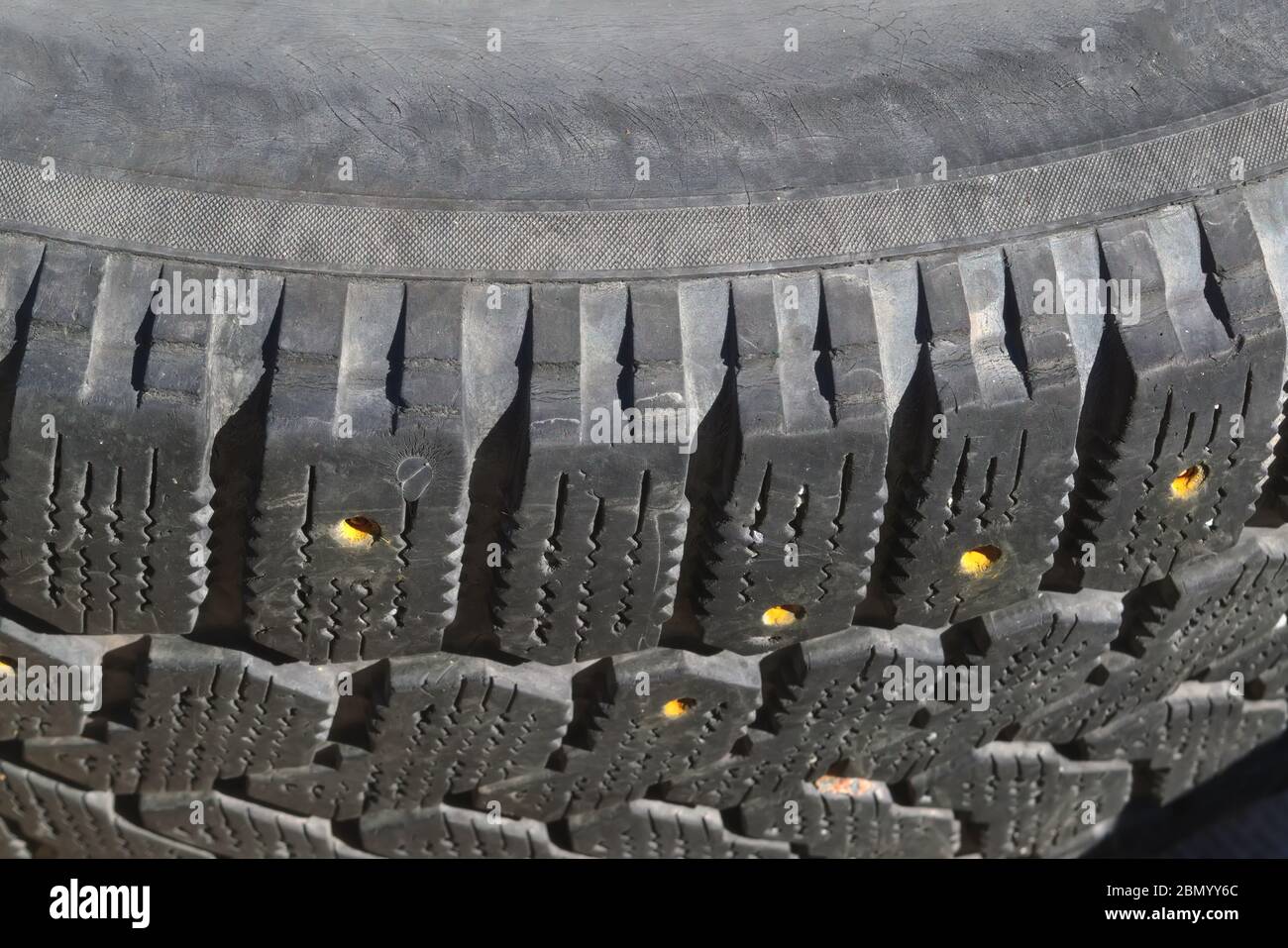 Tread of an old car winter tire with dropped spikes close-up. Worn ...