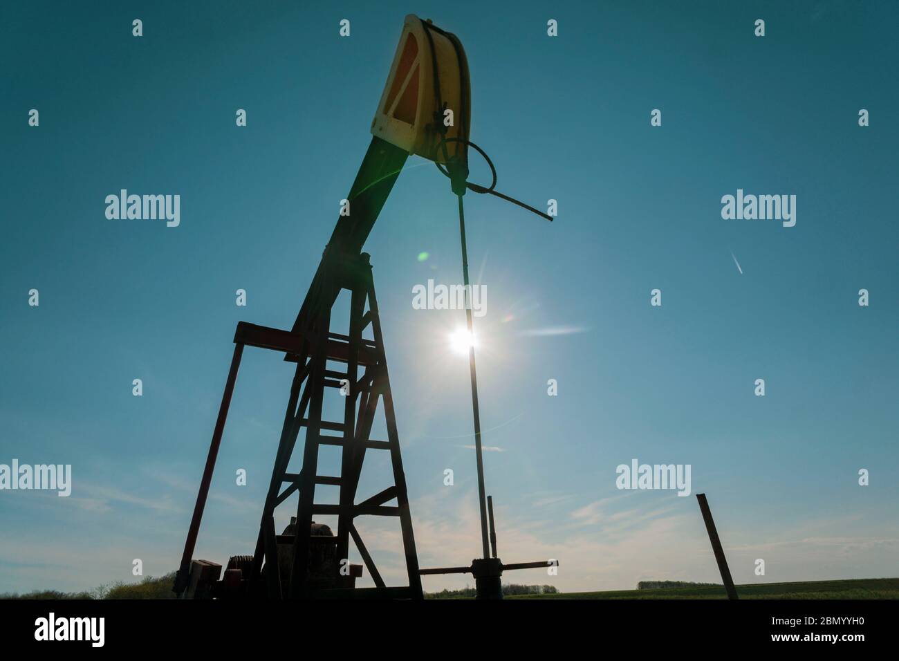 OIL PUMP MACHINE CRANE WITH SUN IN THE BACKGROUND IN CONTRE JOUR Stock ...