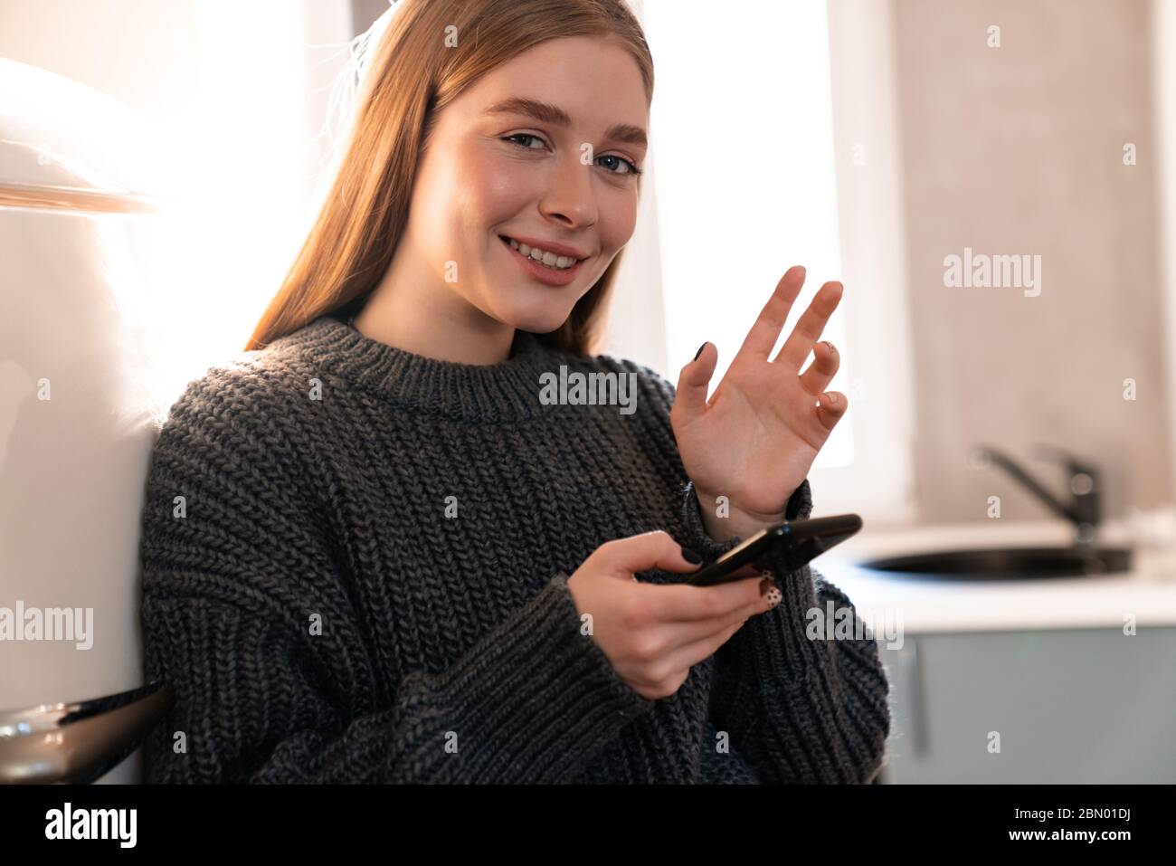 Image of a pleased positive young woman indoors at home using mobile ...
