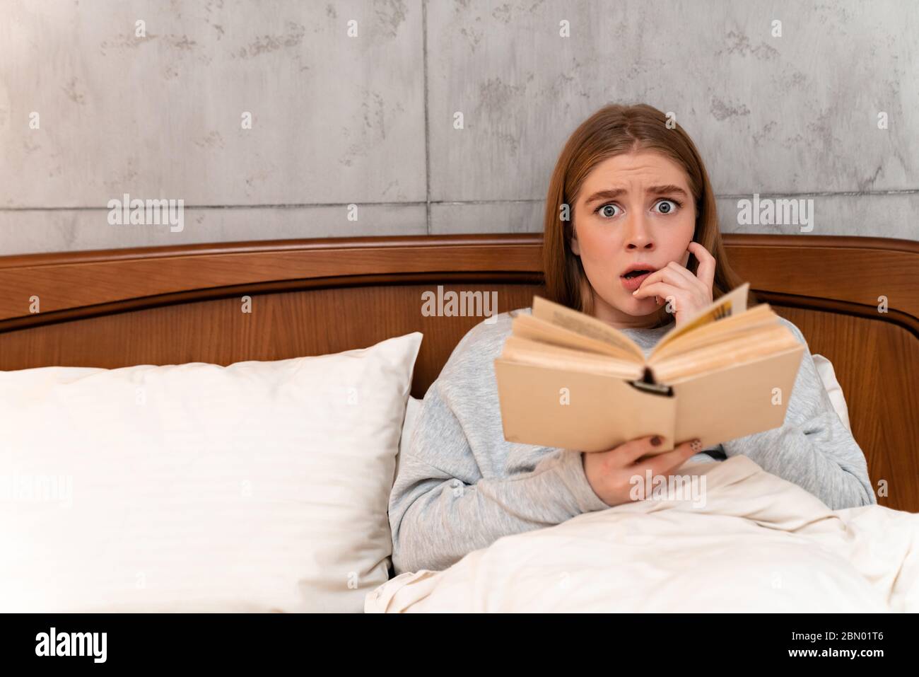 Photo of a shocked scared pretty young woman indoors at home in bed ...