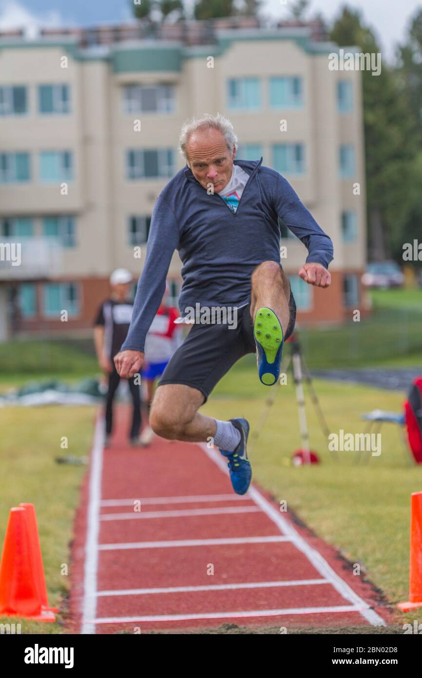 Competing in Men's senior long jump, caught in mid air Stock Photo - Alamy