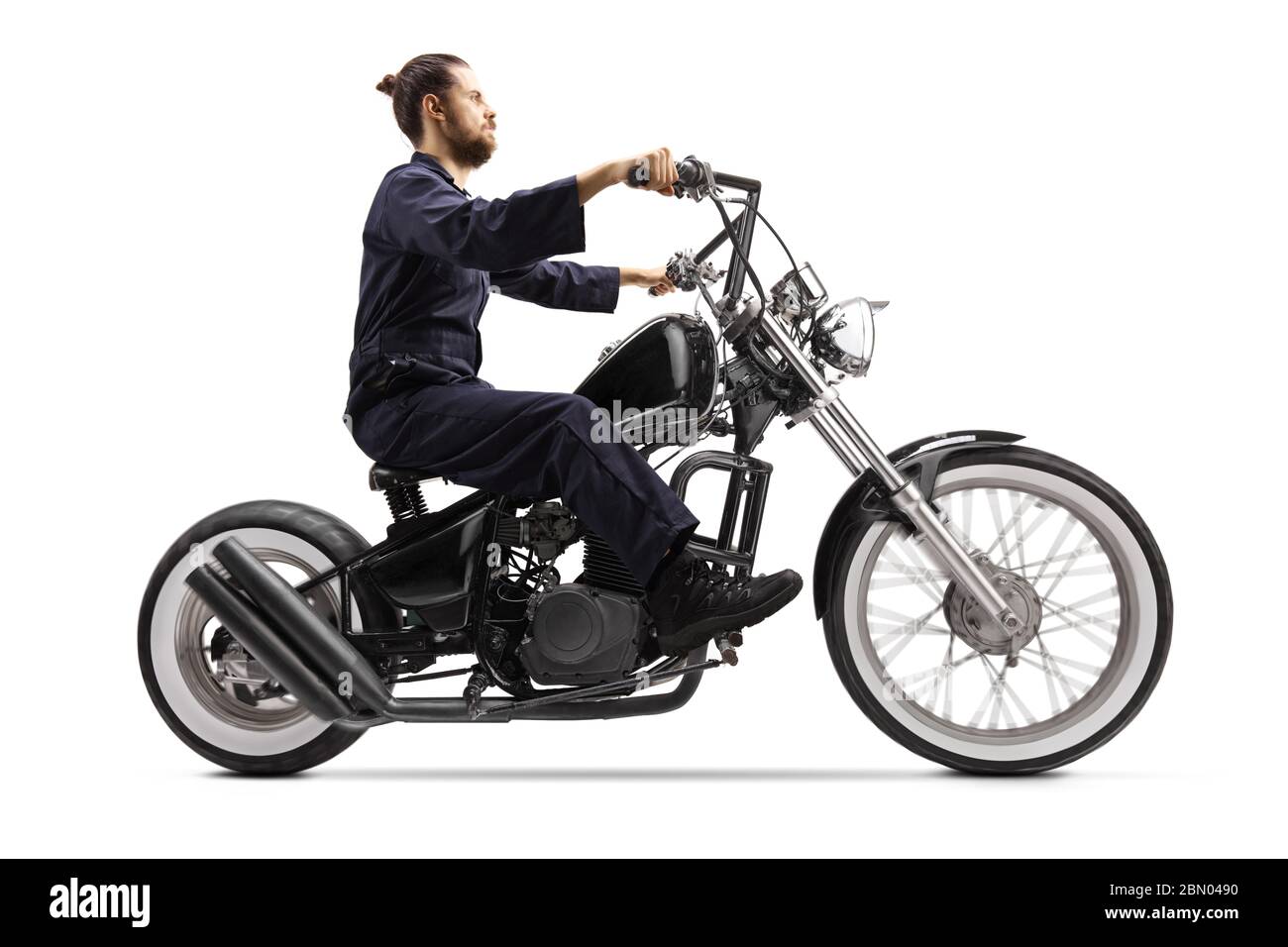Full length profile shot of a mechanic riding a chopper motorbike ...