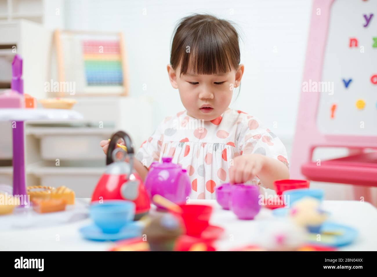 toddler girl prerend play preparing tea party at home Stock Photo - Alamy