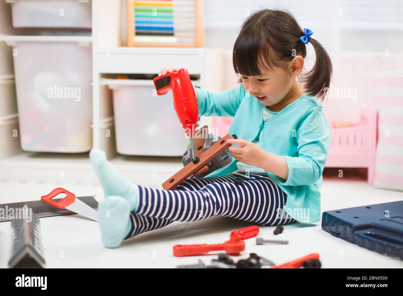 toddler girl pretend using DIY tool at home against white backgrround ...