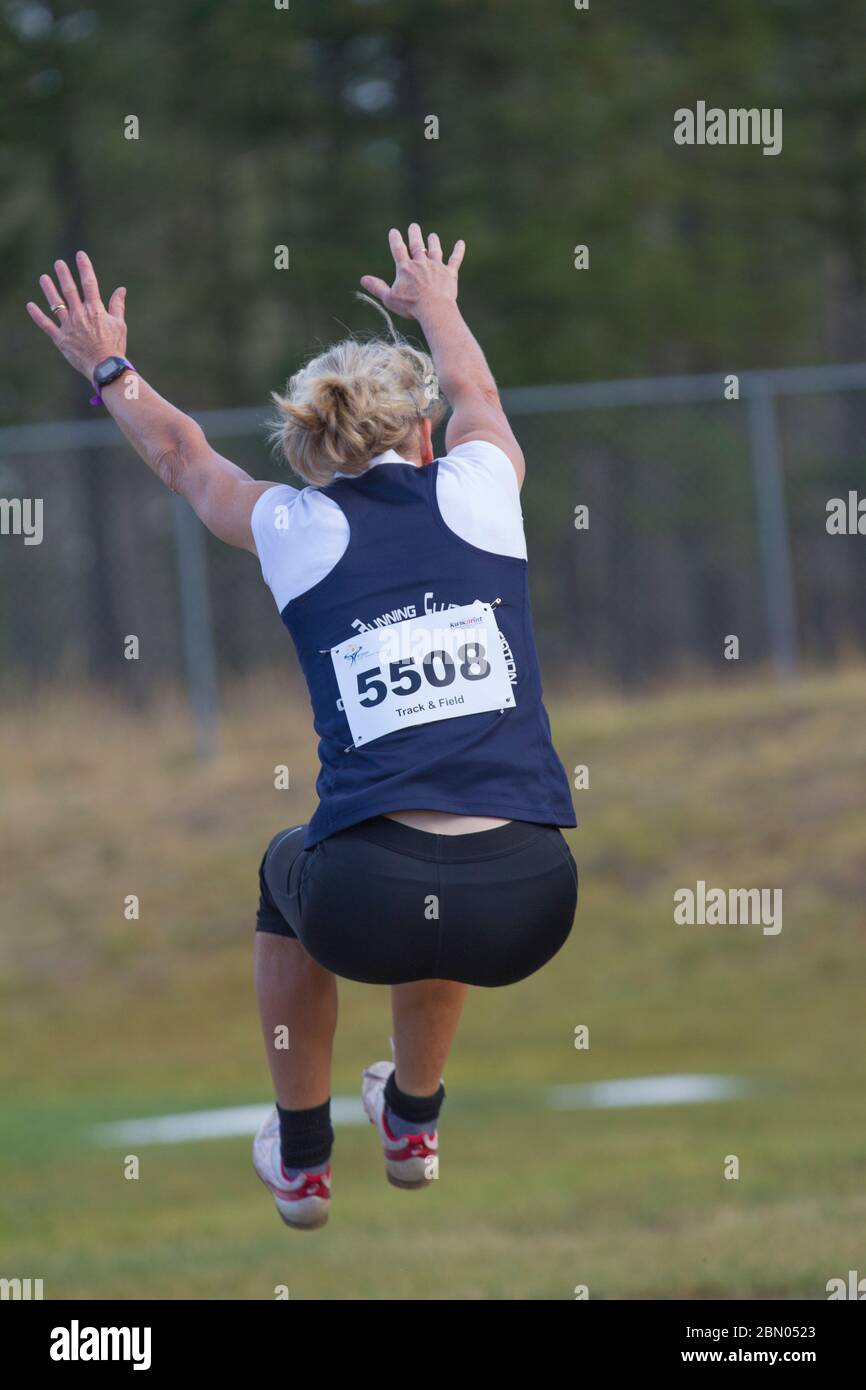 Senior ladies, long jump competition. 55 year old female mid air, haed ...