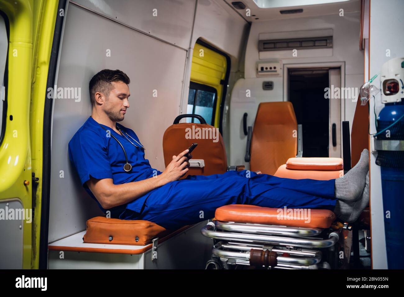 Young corpsman sitting with his phone in the ambulance car Stock Photo ...