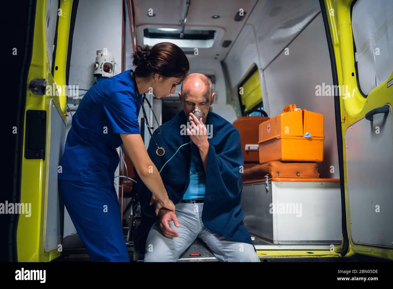 A paramedic is checking the hand of a man rescued from the fire, there ...