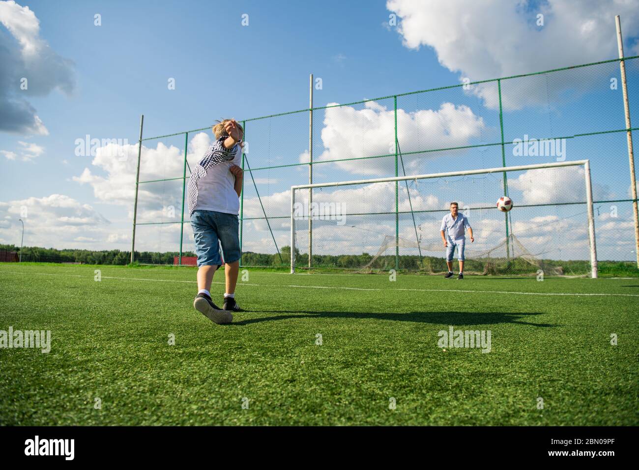Happy father and excited son playing together soccer on a green ...