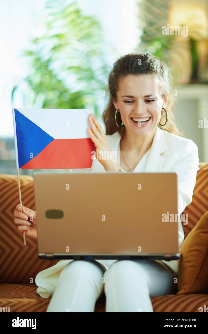 smiling trendy woman in white blouse and jacket with laptop having ...