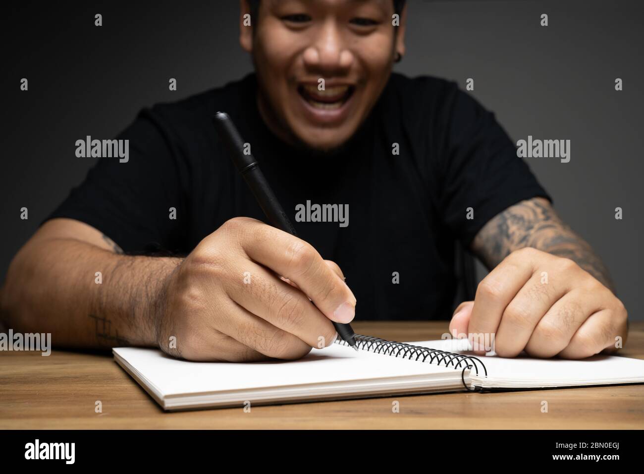 Asian man writing on a note book with happy face on wooden table and ...