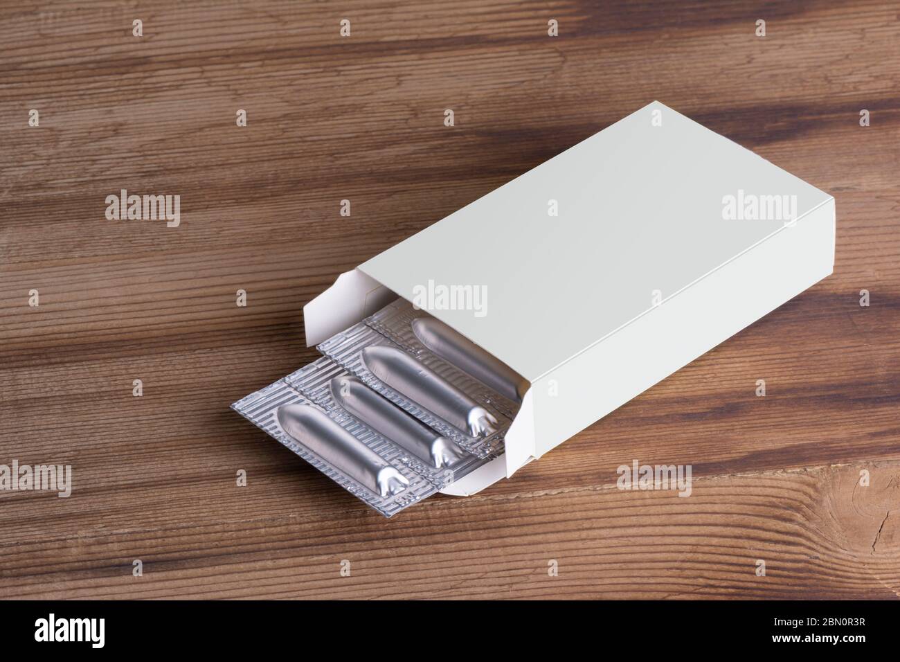 Suppositories loafs inside box on wooden table background, editable ...