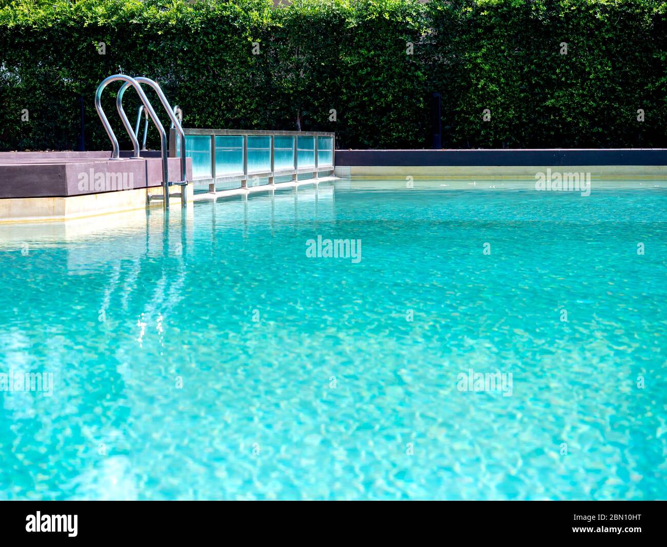 Swimming pool. Stair in outdoor swimming pool near green bush in luxury ...