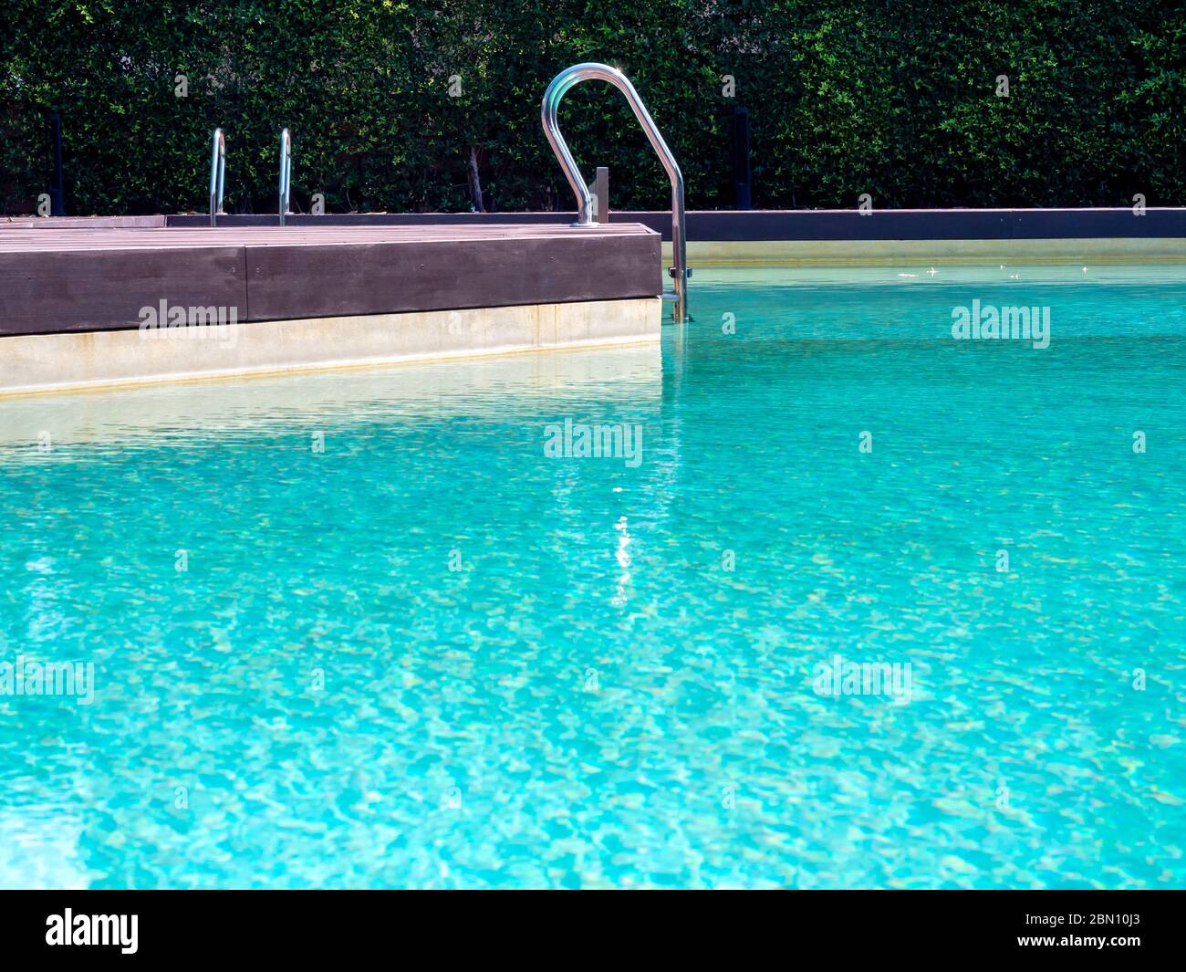 Swimming pool. Stair in outdoor swimming pool near green bush in luxury ...