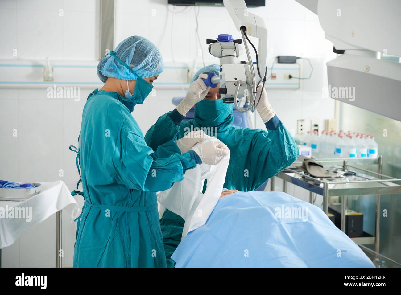 Surgeon and assistant preparing patient for vision restoration ...