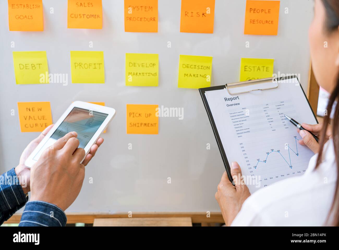 Business people arranging sticky notes commenting and brainstorming on ...