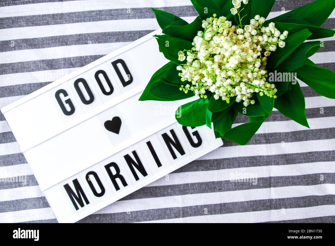 Lightbox with text GOOD MORNING and bouquet lilies of the valley in ...