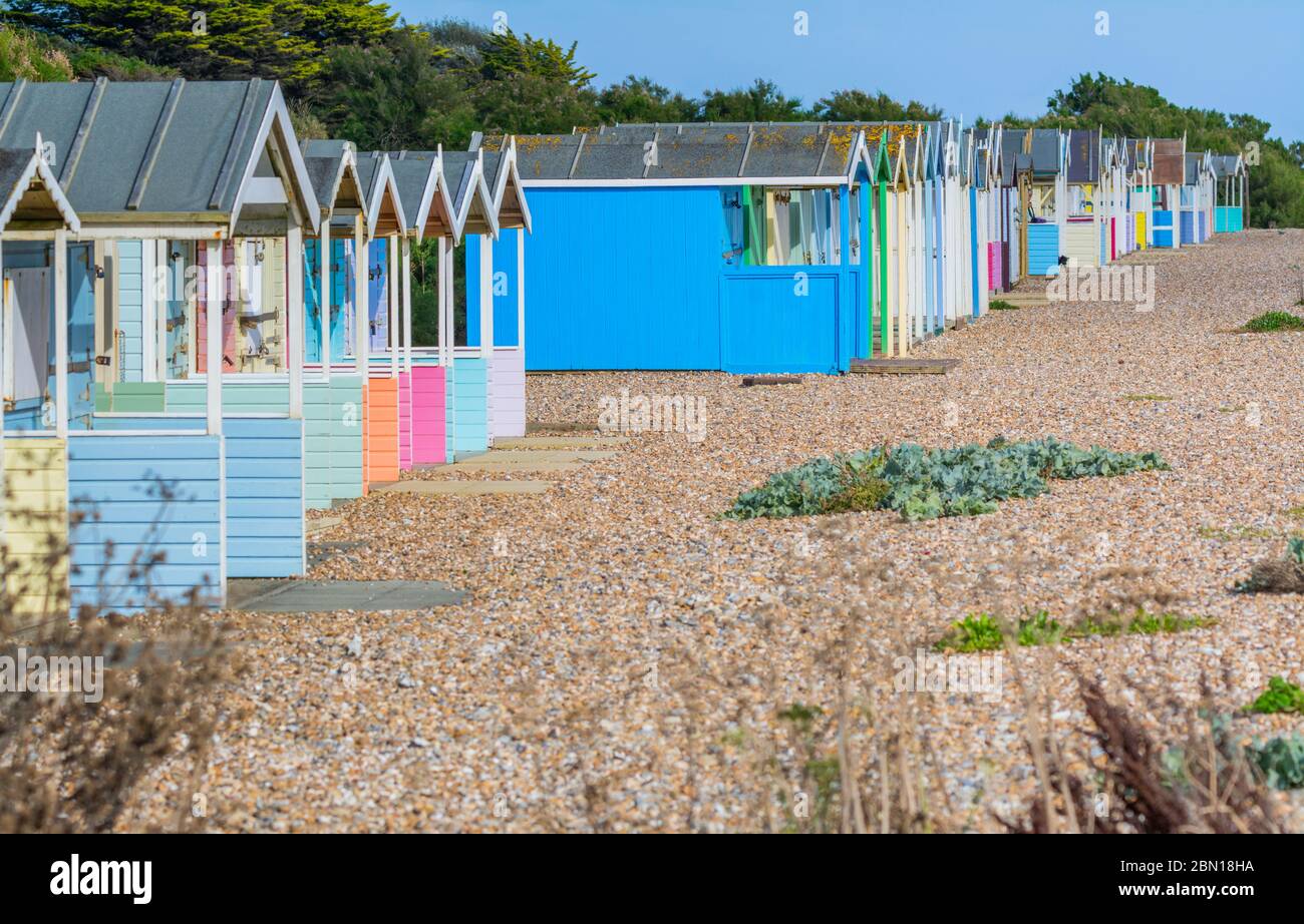 Row of old multicoloured beach huts on a shingle beach in Rustington ...