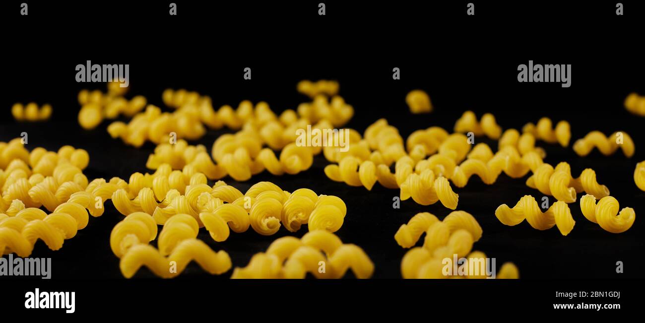 Italian raw pasta on black background. macaroni cellentani Stock Photo ...