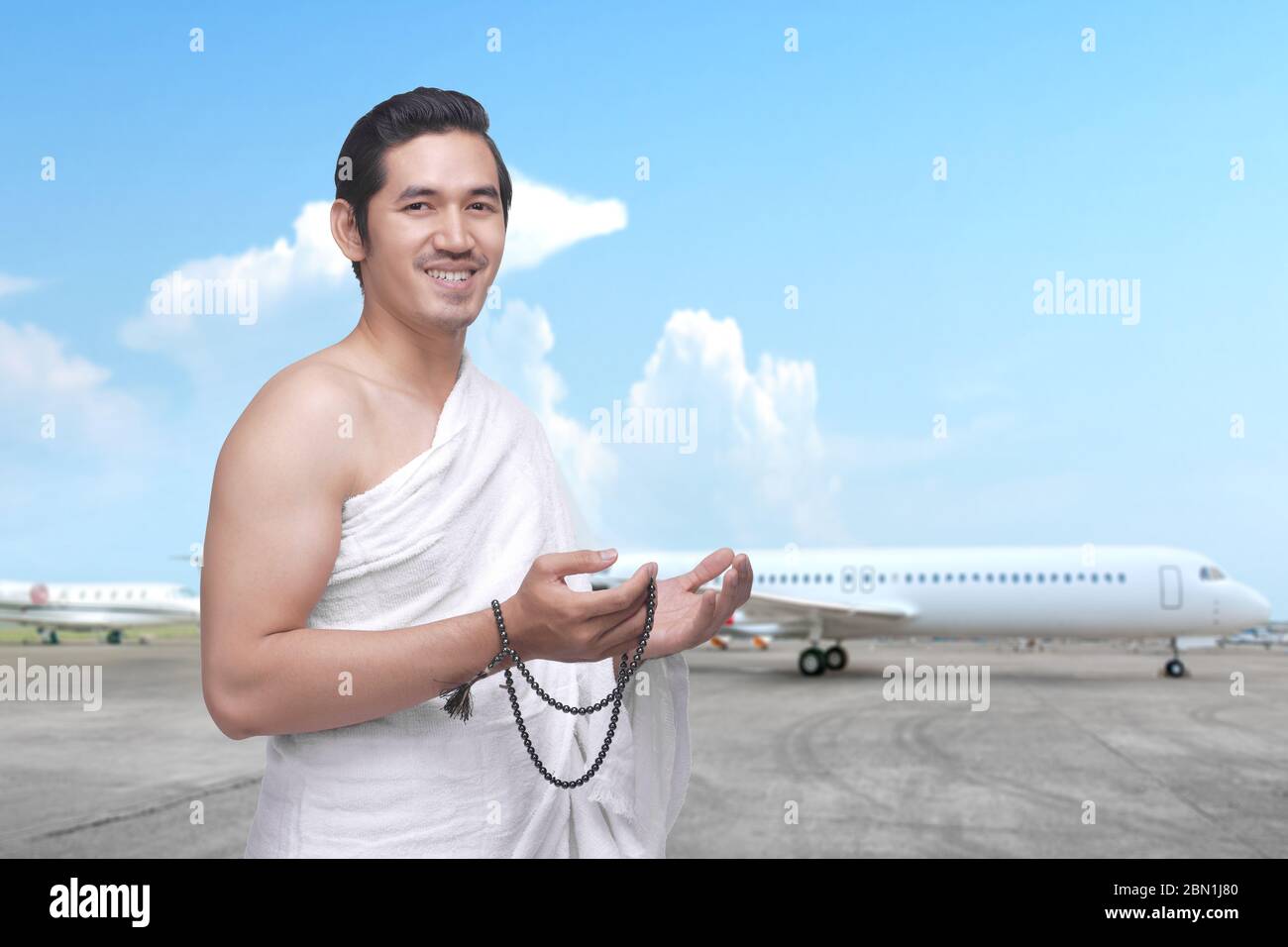 Asian Muslim man in ihram clothes with prayer beads on his hands going ...