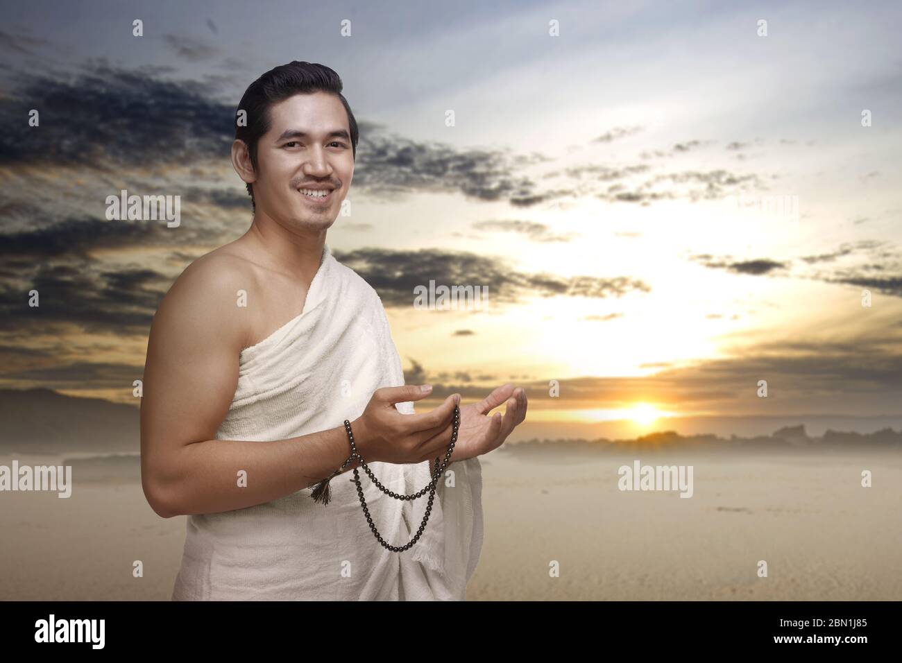 Asian Muslim man in ihram clothes praying with prayer beads on his ...