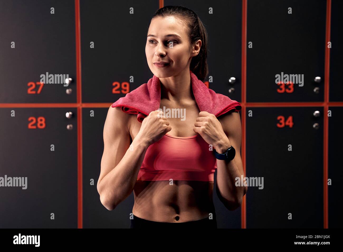 Young adult athlete woman standing in locker room with towel Stock Photo - Alamy