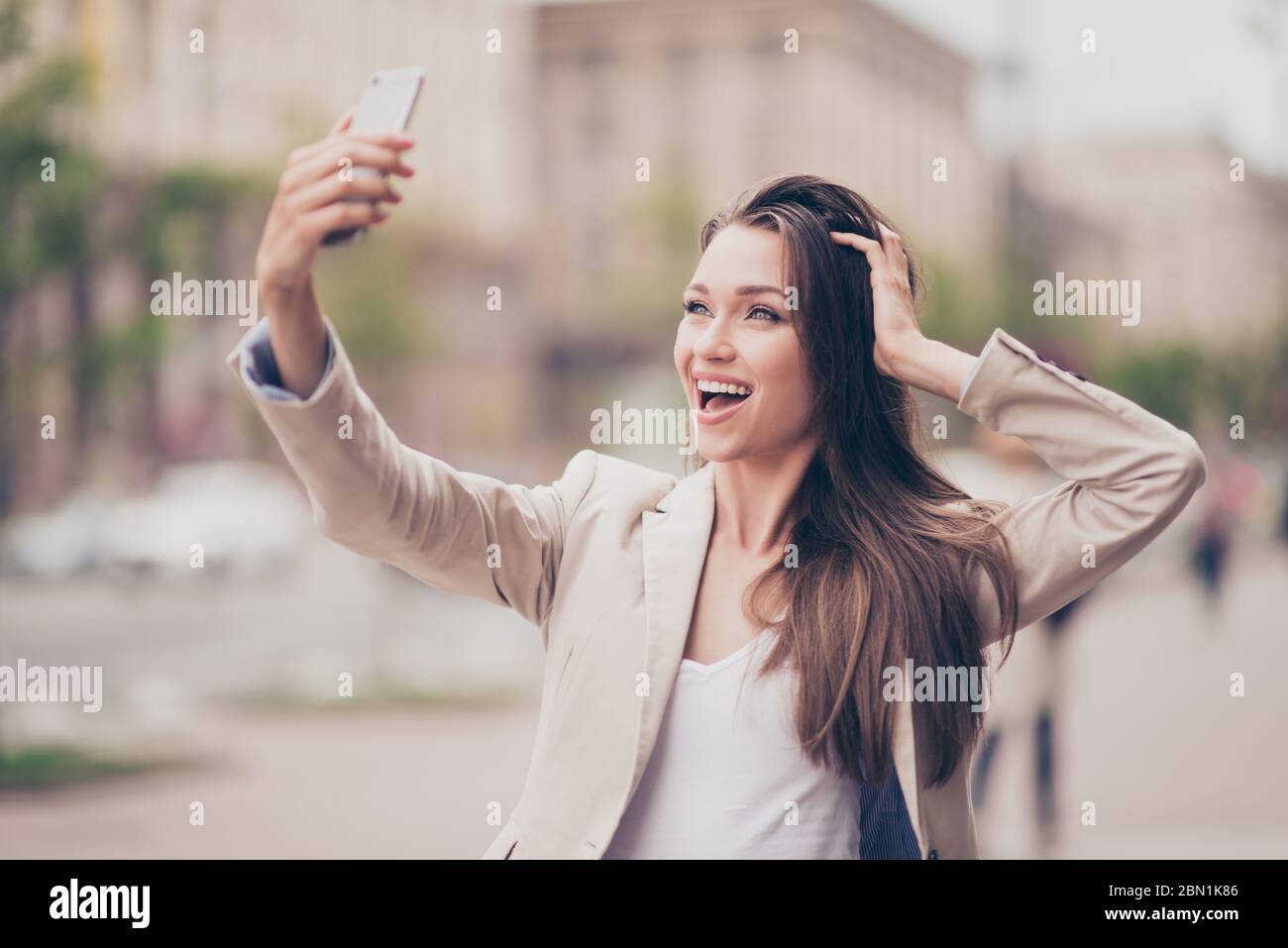 Selfie mania! Excited young girl is making selfie on a camera. She is wearing formal wear ...