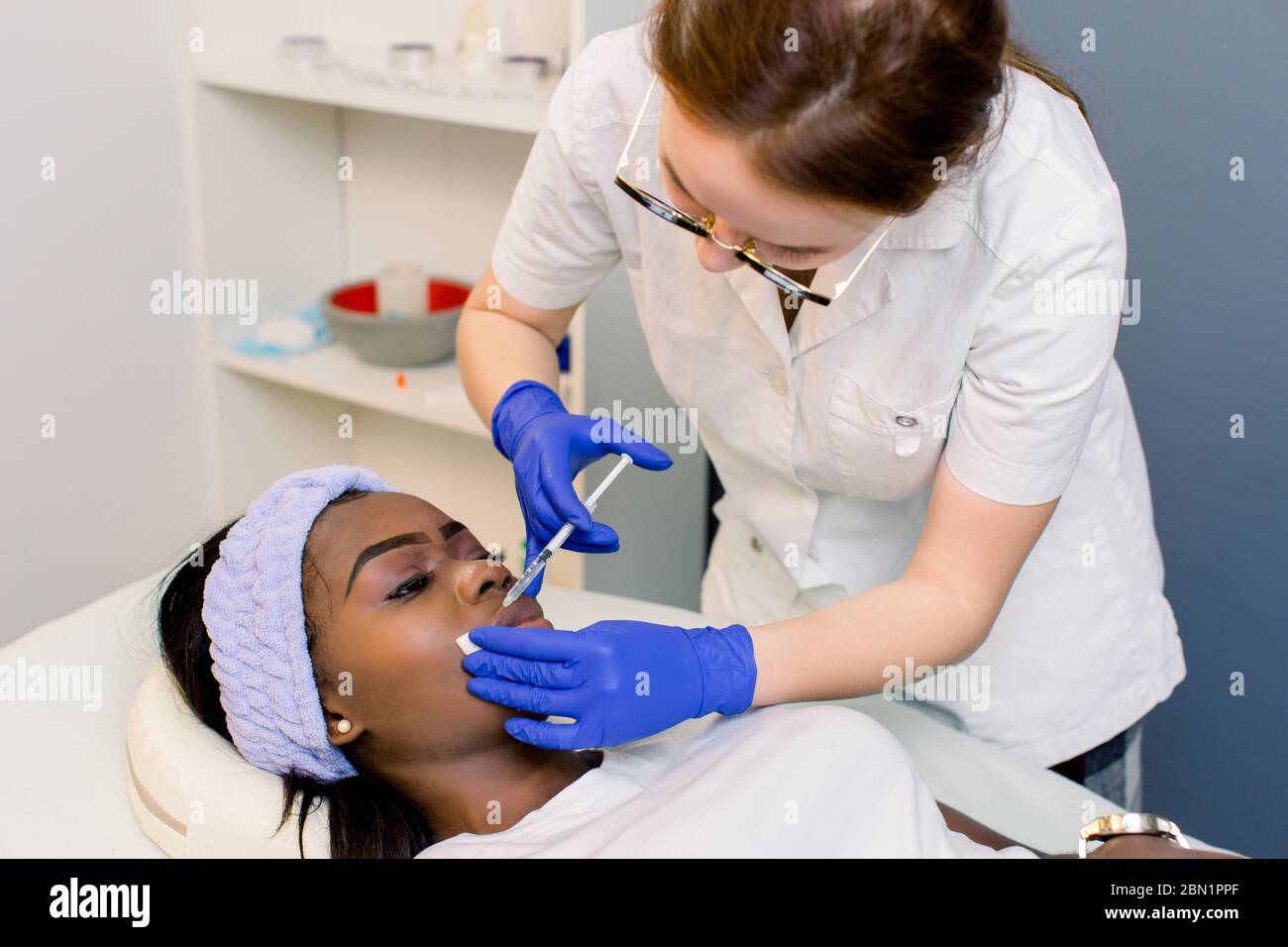 The doctor cosmetologist makes Lip augmentation procedure of a ...